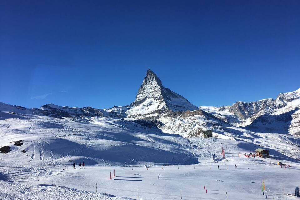 Pista de esqui coberta de neve com um pico de montanha imponente ao fundo.
