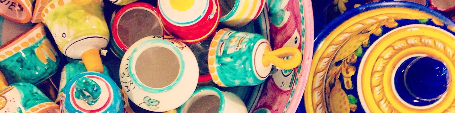 Uma variedade de canecas e xícaras de cerâmica coloridas, com desenhos elaborados.