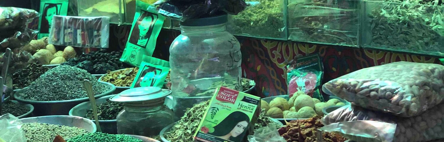 Uma banca de mercado com diversos temperos e ervas expostos em tigelas e recipientes.