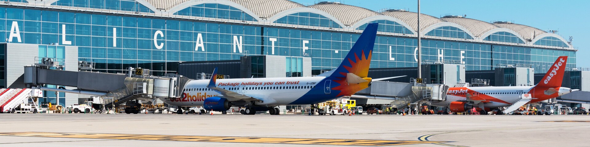 Um aeroporto com um grande edifício terminal e vários aviões estacionados no tarmac.