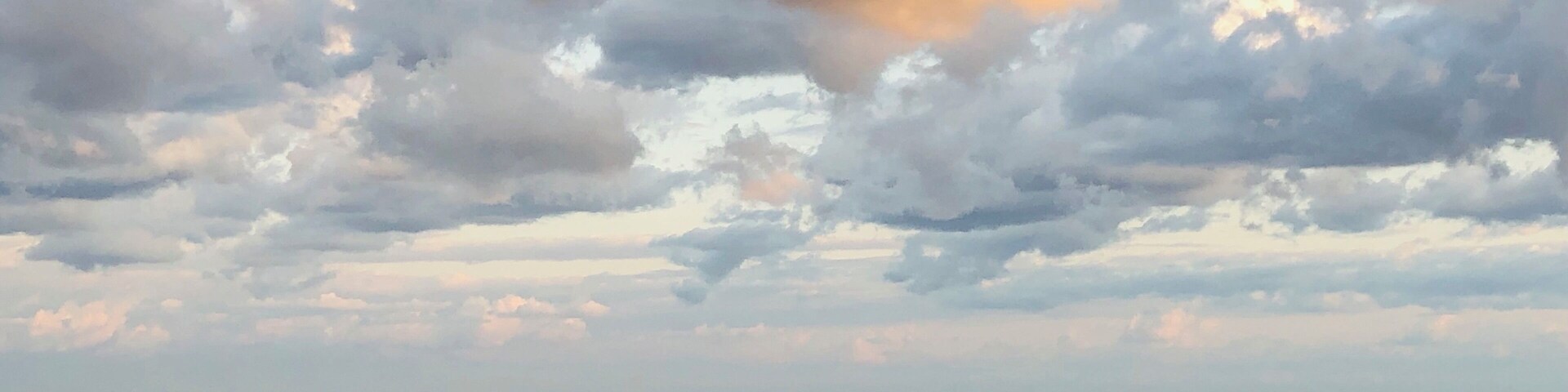 Paisagem costeira com vista para o mar, um barco e edifícios sob um céu nublado.