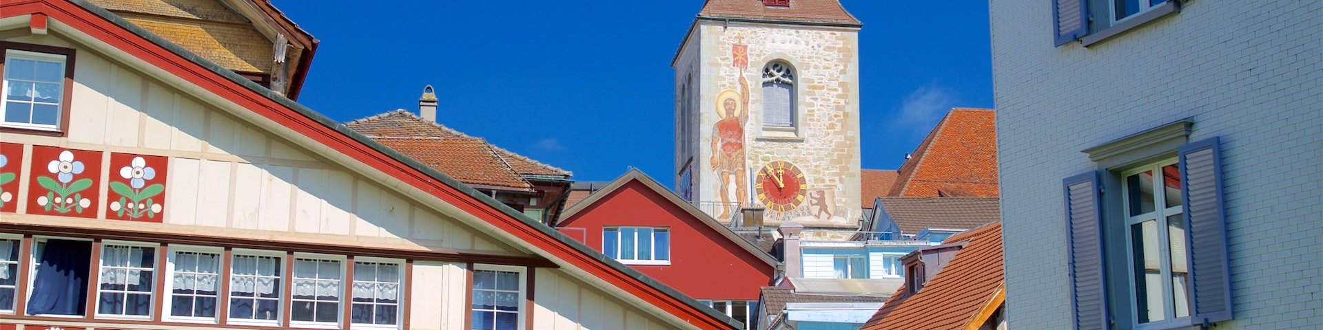 Uma cidade com edifícios coloridos, uma torre de igreja e um céu azul límpido.