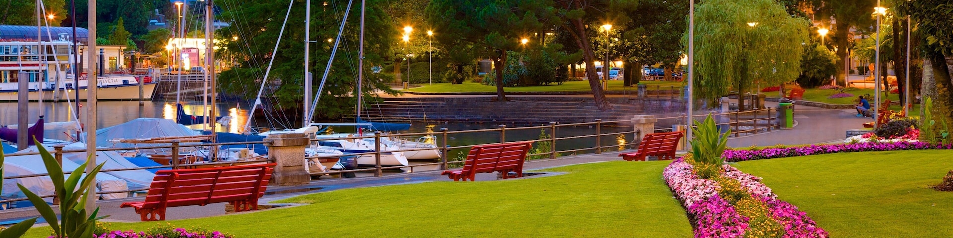Uma marina com barcos, bancos e um jardim de flores.