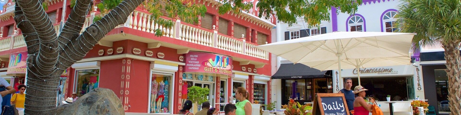 Mercado ao ar livre vibrante com edifícios coloridos, uma palmeira e um aviso oferecendo promoção de happy hour.
