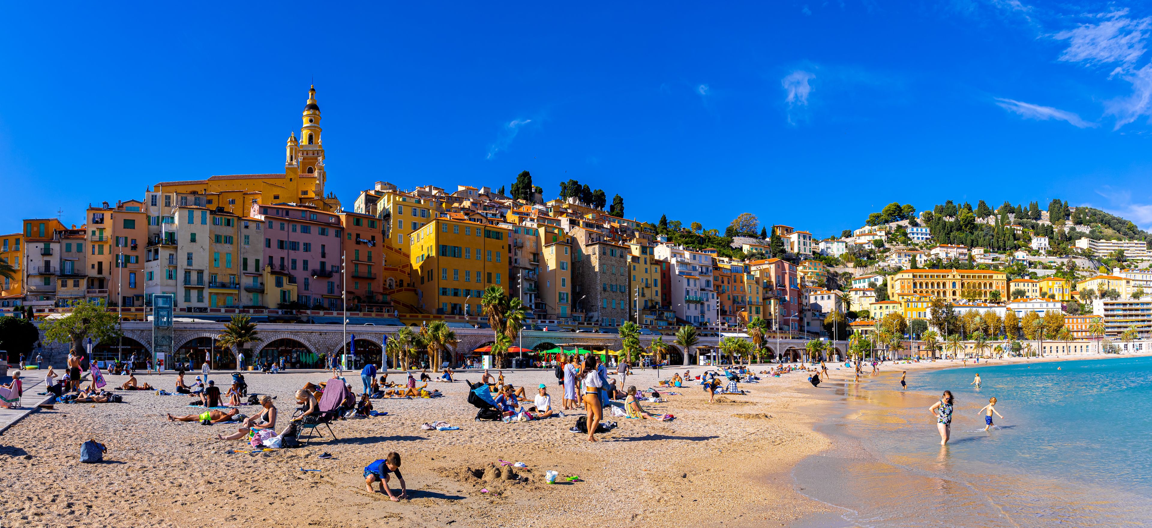 Uma cidade costeira com edifícios coloridos, uma praia e águas azul-claras.