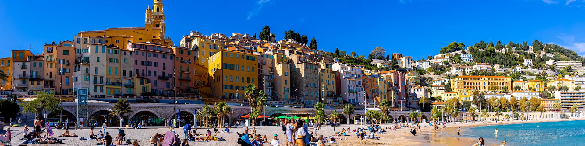 Uma cidade costeira com edifícios coloridos, uma praia e águas azul-claras.