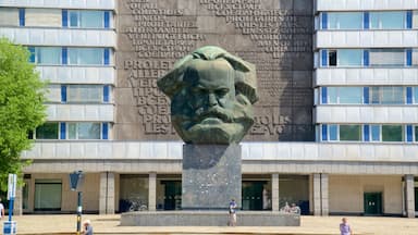 Um grande monumento de pedra com inscrições em várias línguas, situado em frente a um edifício moderno com amplas janelas.