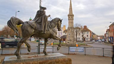 Estátua de um homem a cavalo numa praça pública, com o topo de uma igreja ao fundo.