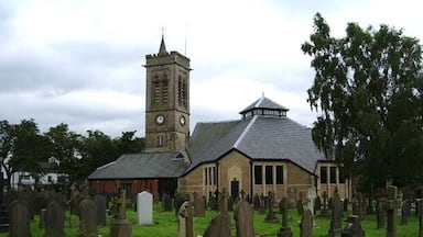 Igreja com torre do relógio e cemitério com lápides.