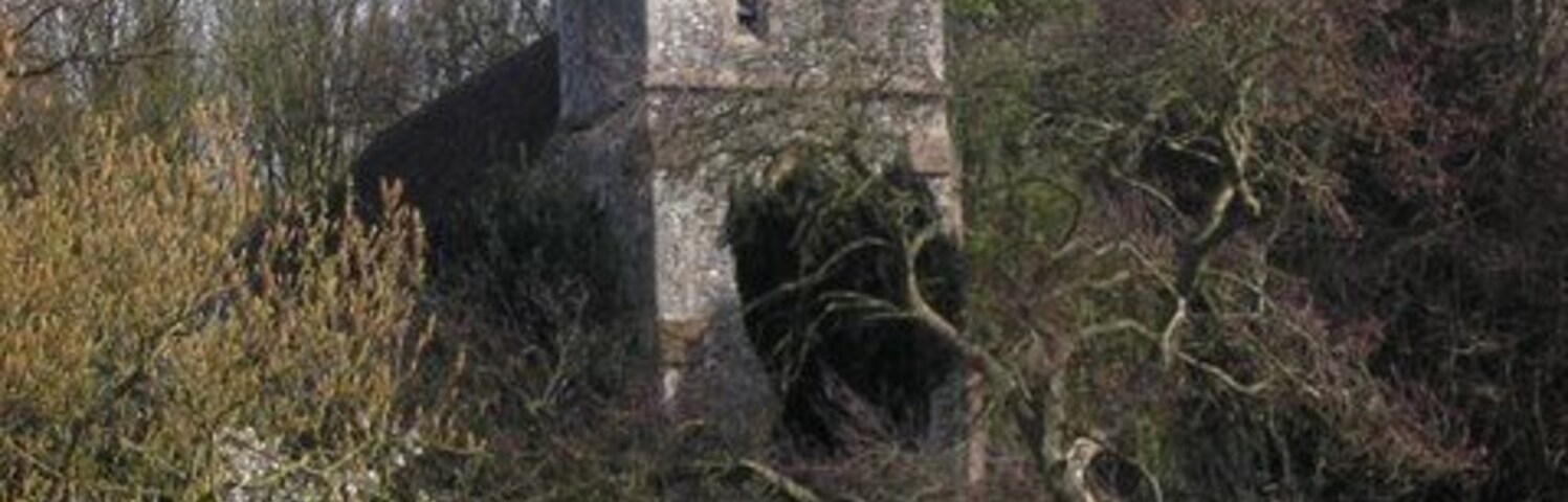 Uma torre de pedra com janelas em arco, rodeada por árvores e relva.