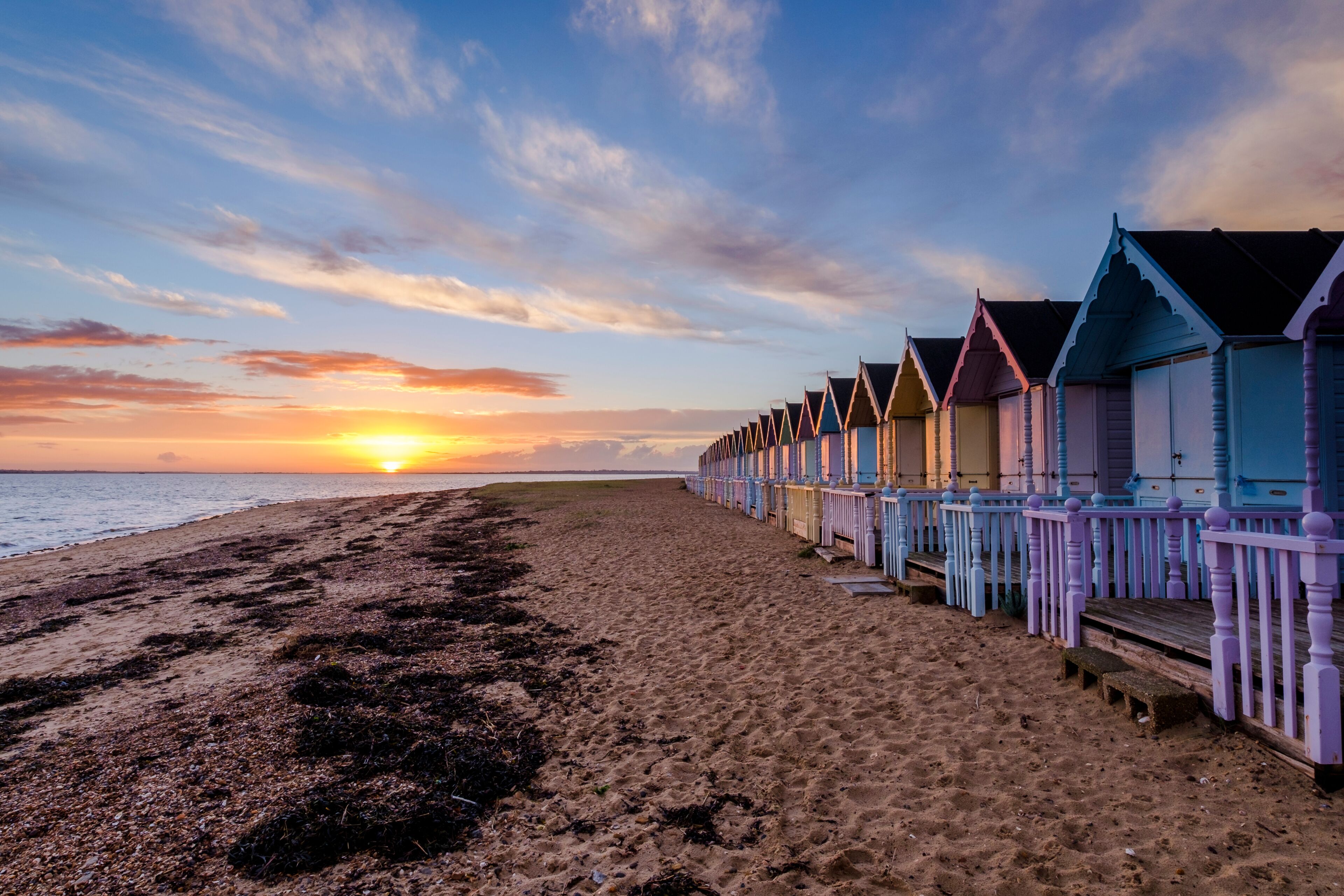Uma praia com cabanas de madeira e um pôr do sol.