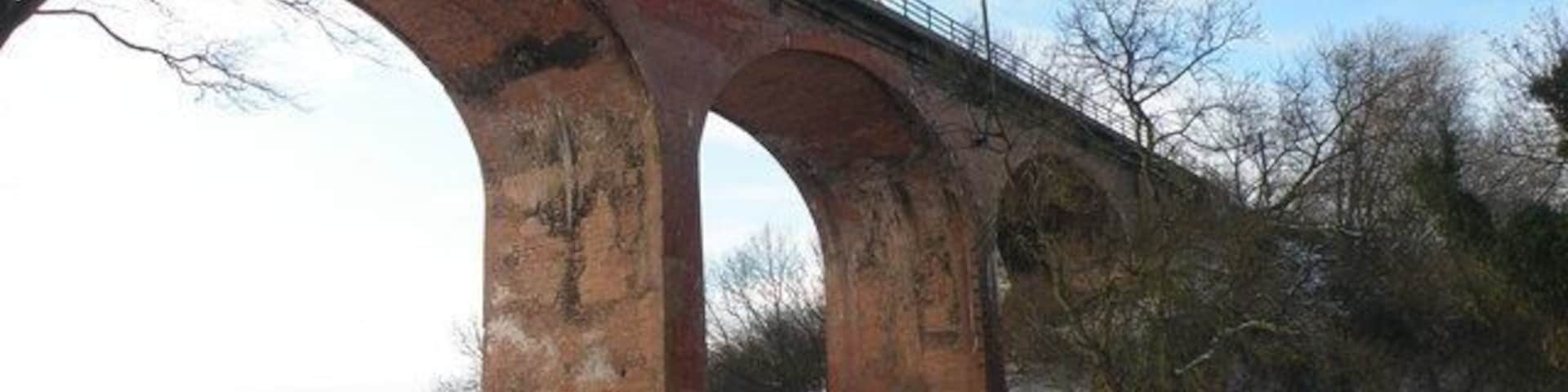 Uma ponte de tijolos com três arcos sobre um caminho coberto de neve.