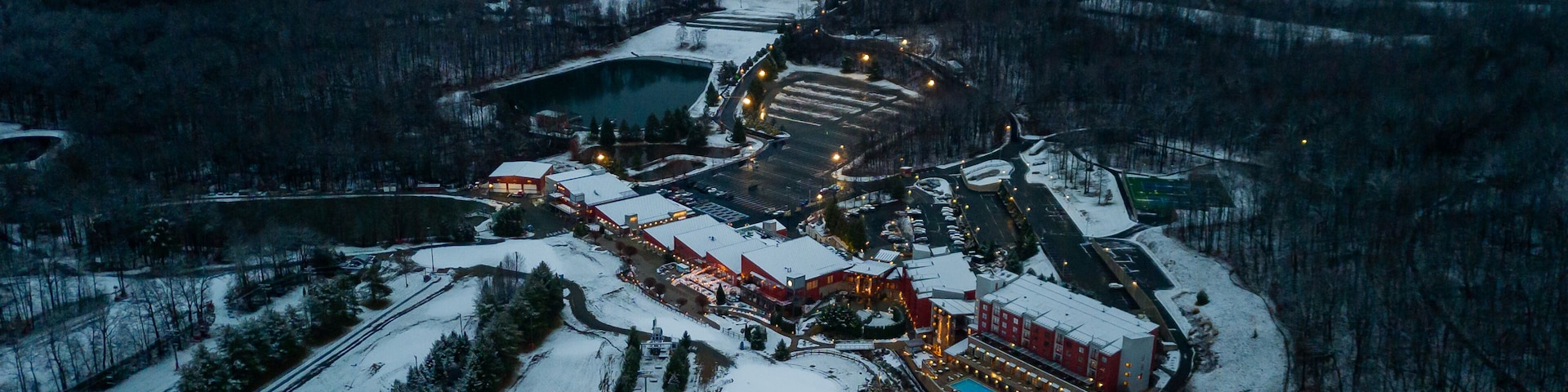 Estância de esqui coberta por neve, com vários edifícios e um teleférico.