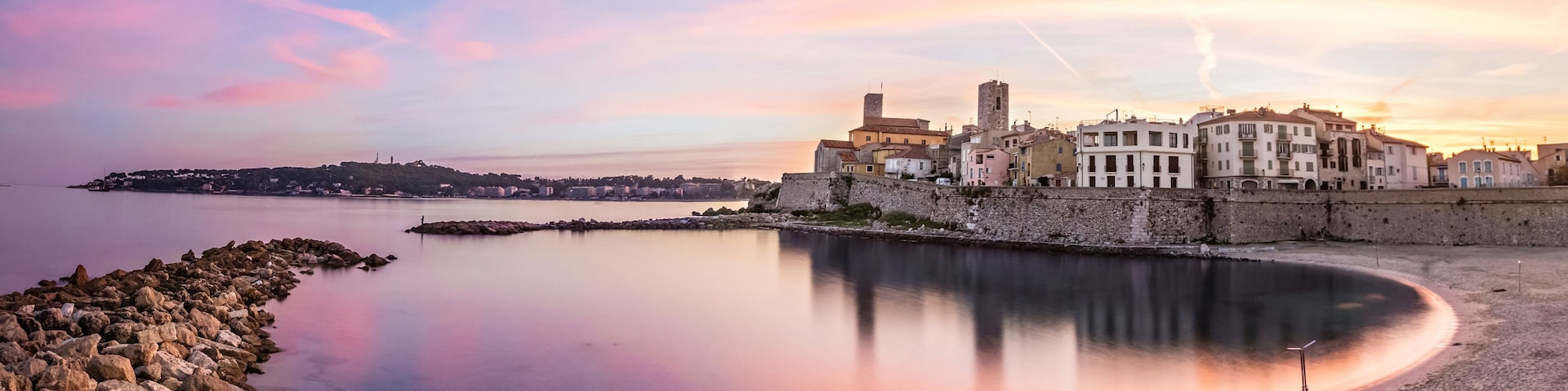 Uma cidade costeira com uma baía tranquila, edifícios históricos e uma parede de pedra.