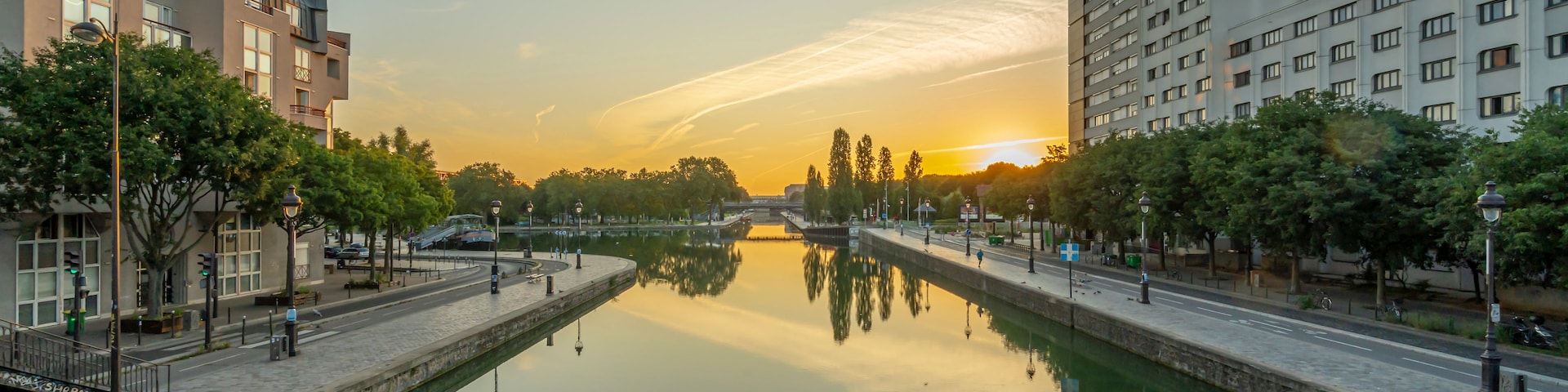 Um canal ladeado por edifícios, céu claro e pôr do sol.