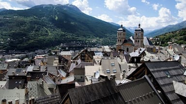 Uma cidade com edifícios históricos e montanhas ao fundo.