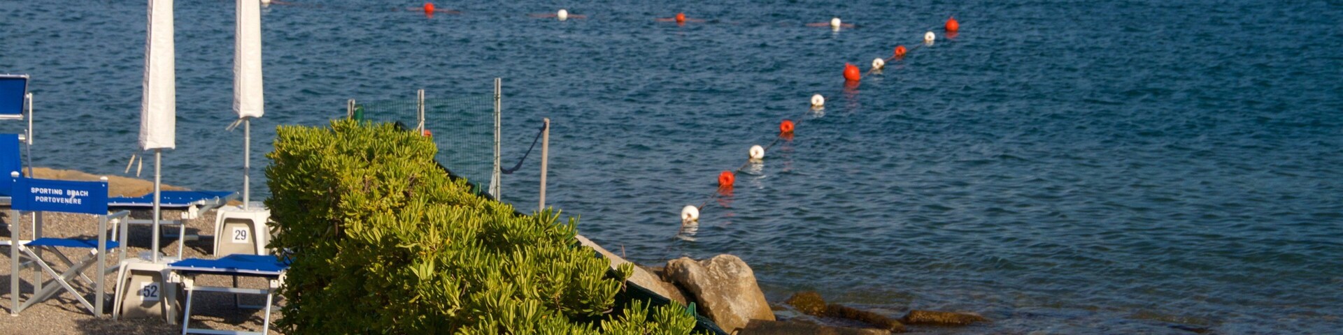 Um porto com barcos, boias e uma fileira de cadeiras de praia.