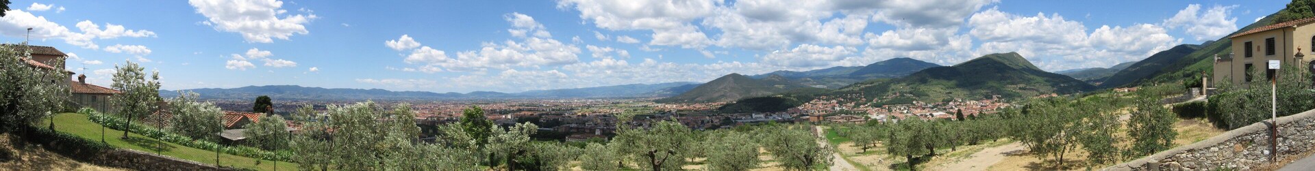 Vista panorâmica de uma cidade aninhada num vale, com montanhas ao fundo.