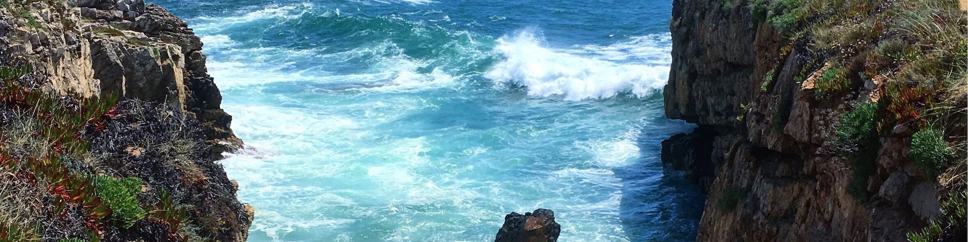 Paisagem costeira com falésias rochosas, margem rochosa e o oceano.