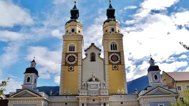 Uma igreja com duas torres, um grande relógio e estátuas em frente.