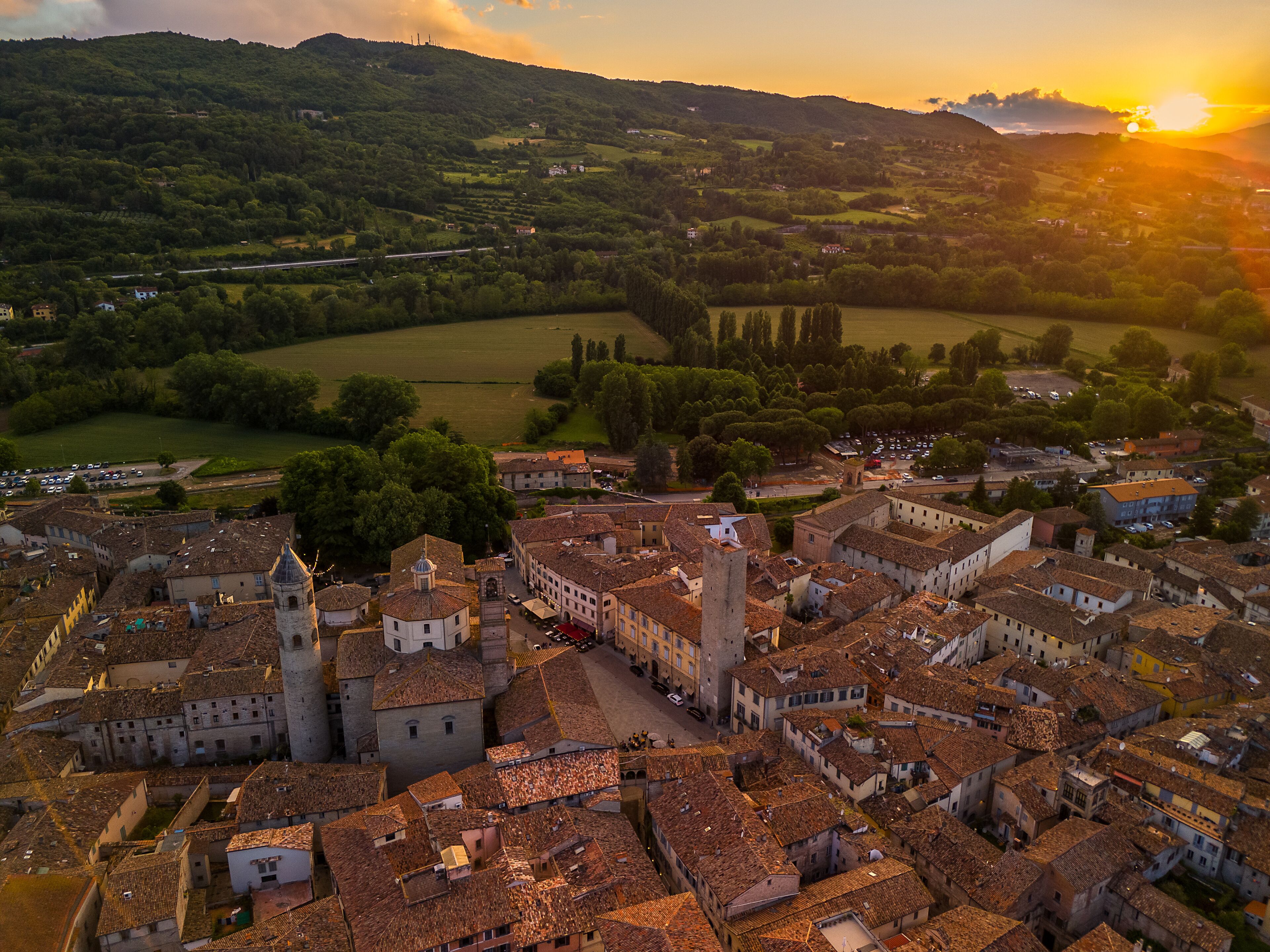 Uma cidade histórica com arquitetura medieval, uma torre imponente e um rio ao fundo.