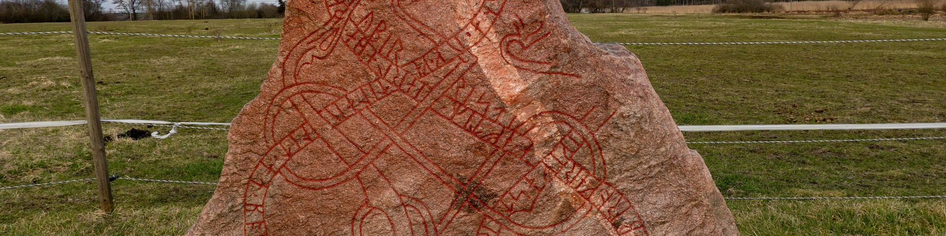 Uma rocha grande com entalhes vermelhos em um campo gramado.