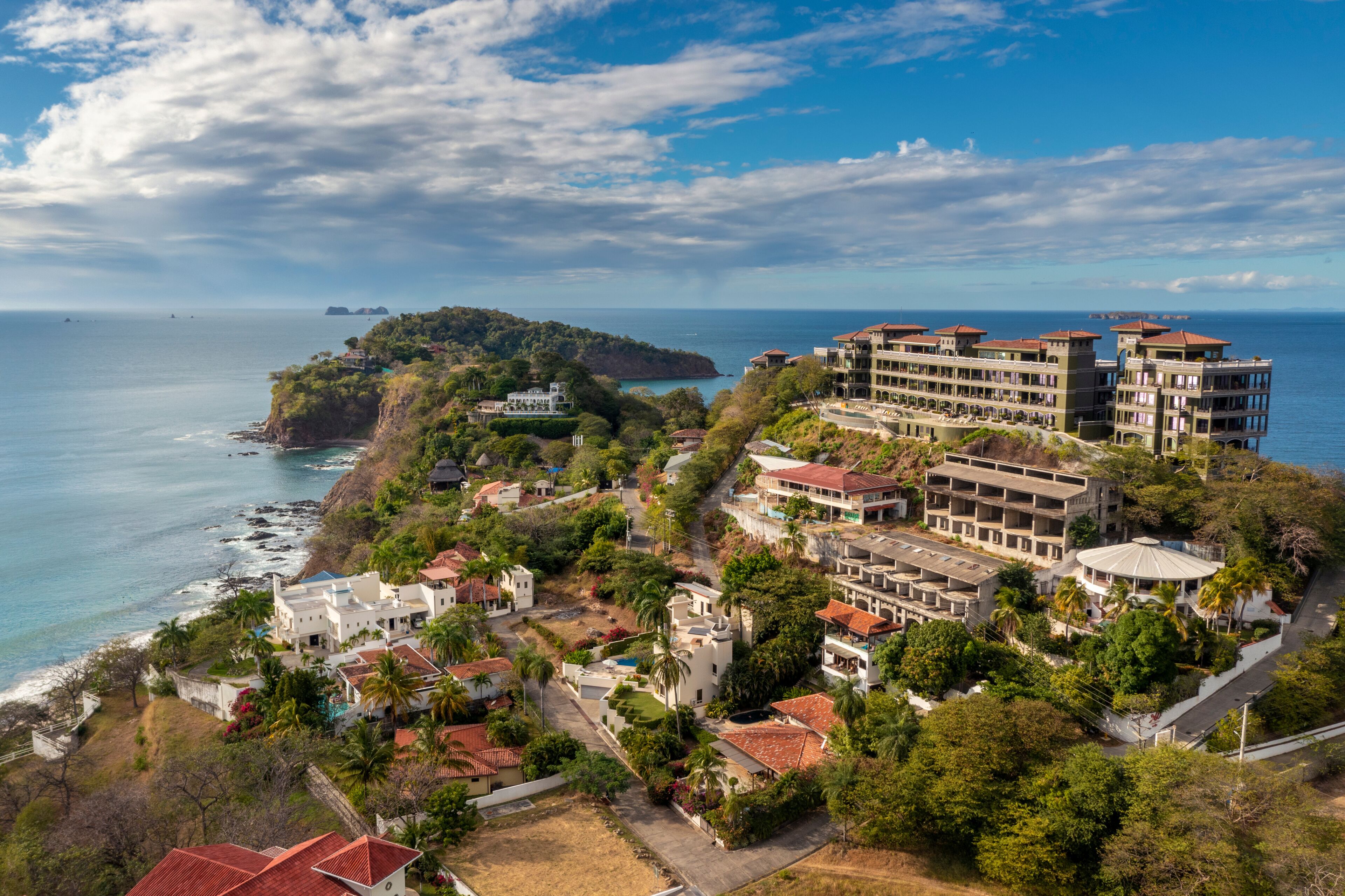 Uma vila costeira com edifícios, uma praia e uma ilha ao longe.