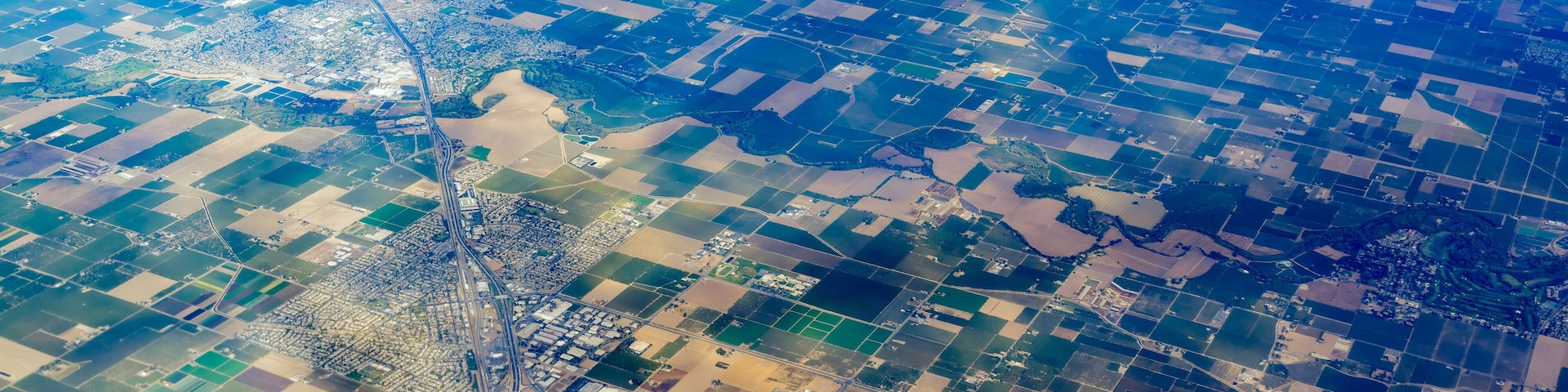 Vista aérea de campos em mosaico e uma estrada sinuosa.