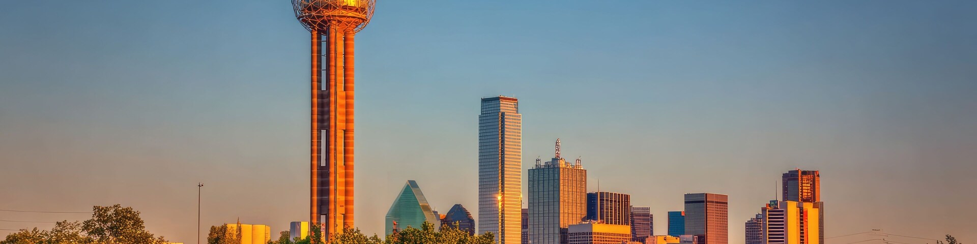 Horizonte urbano com uma torre imponente e edifícios modernos sob um céu límpido.