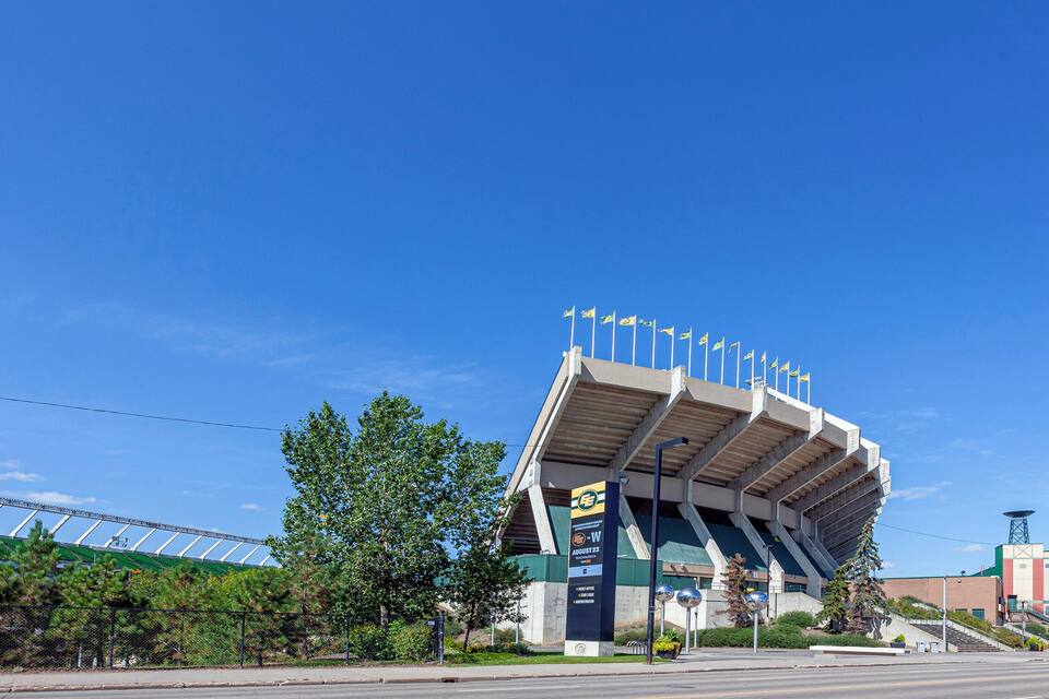 Um estádio com design arquitetônico singular, apresentando uma ampla estrutura de cobertura aberta e várias bandeiras no topo.