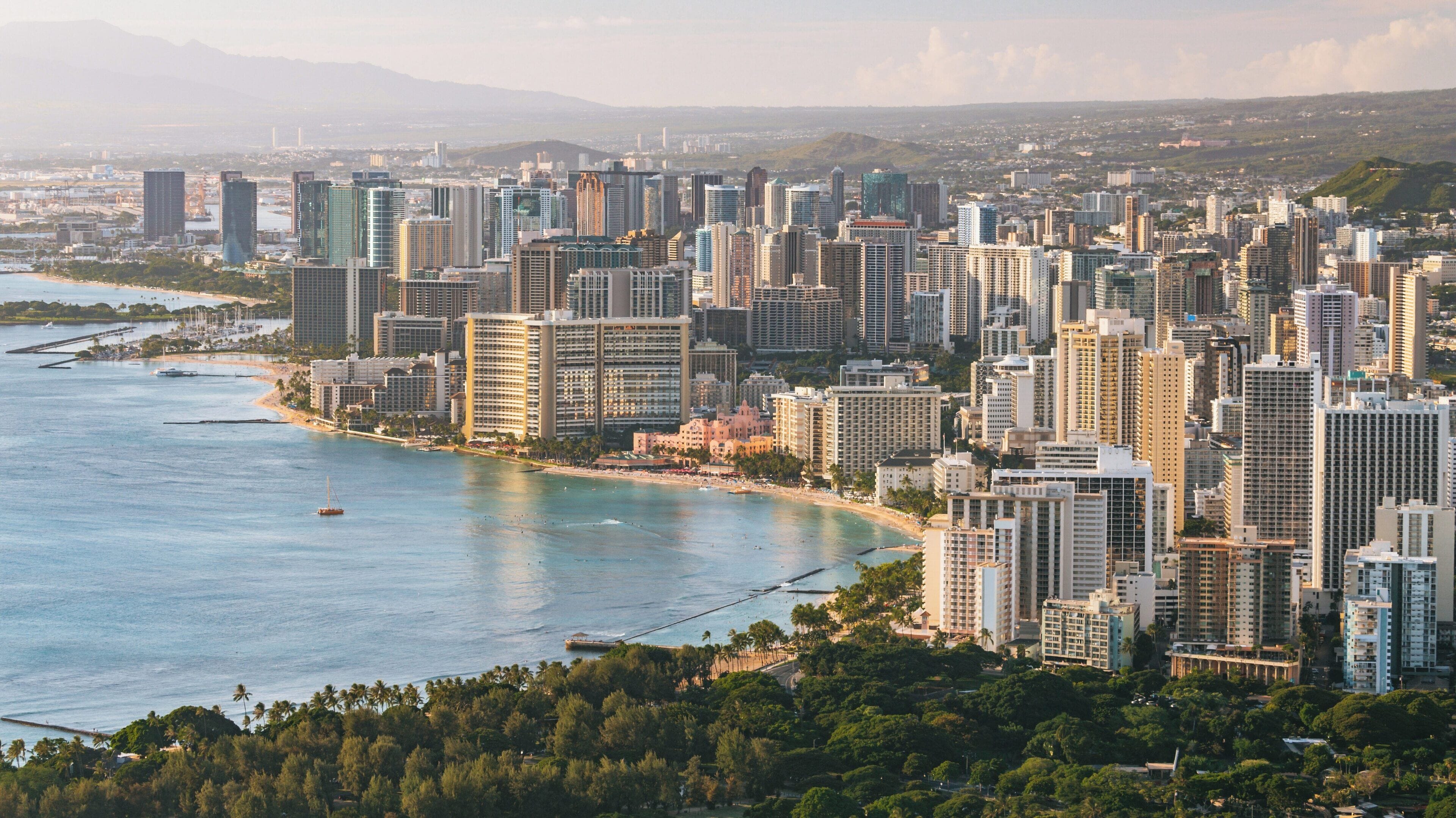 View of Diamond Head and Honolulu skyline from high vantage point during sunset with vibrant clouds and golden reflections on the water