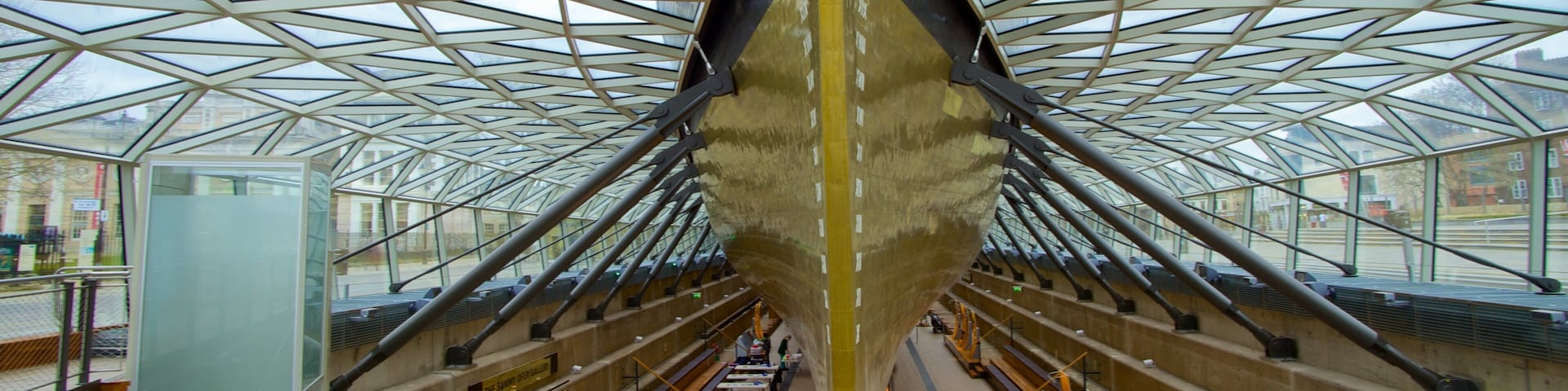 Proa de um grande navio dentro de um edifício moderno com teto de vidro.