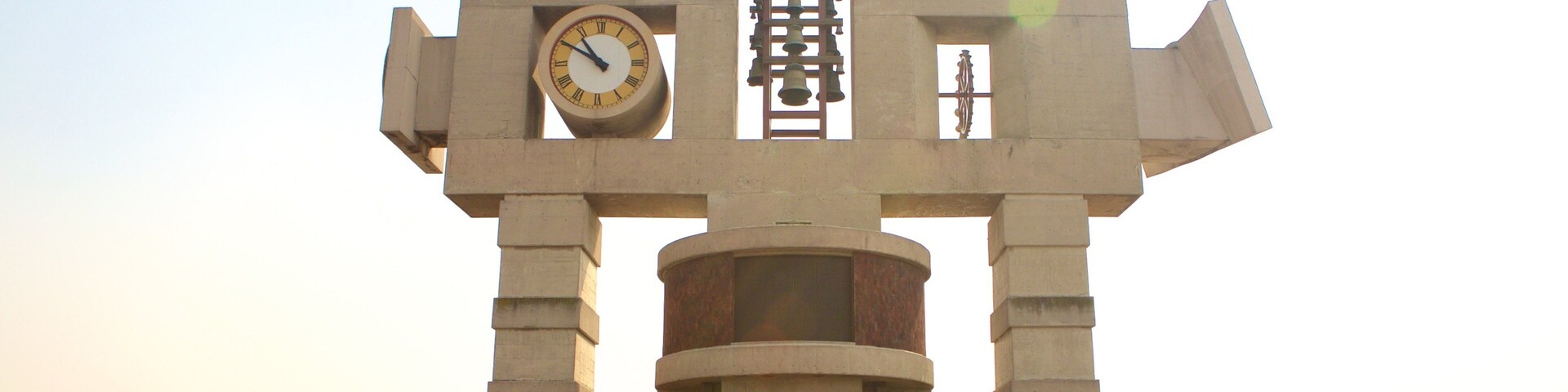 Um grande campanário com um relógio solar no centro, cercado por uma grade e degraus que levam até ele.