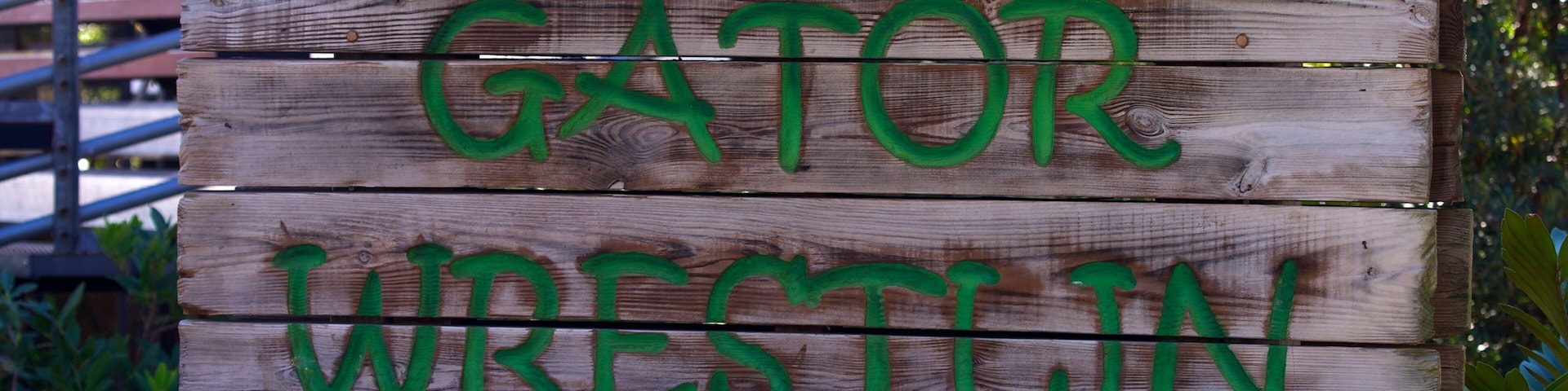 Uma placa de madeira com a inscrição 'GATORLAND'S GATOR WRESTLING' e 'ORLANDO FLORIDA'.