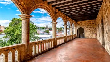 Uma galeria coberta com arcos de pedra e piso de azulejos.