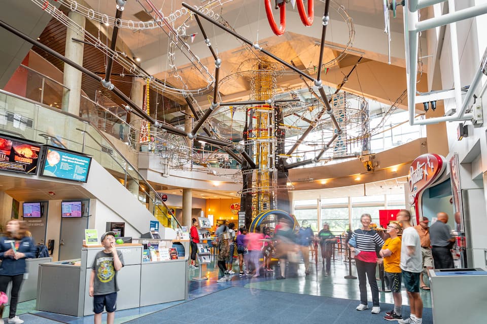 Um movimentado shopping center com pé-direito alto, decorações suspensas e diversas lojas.