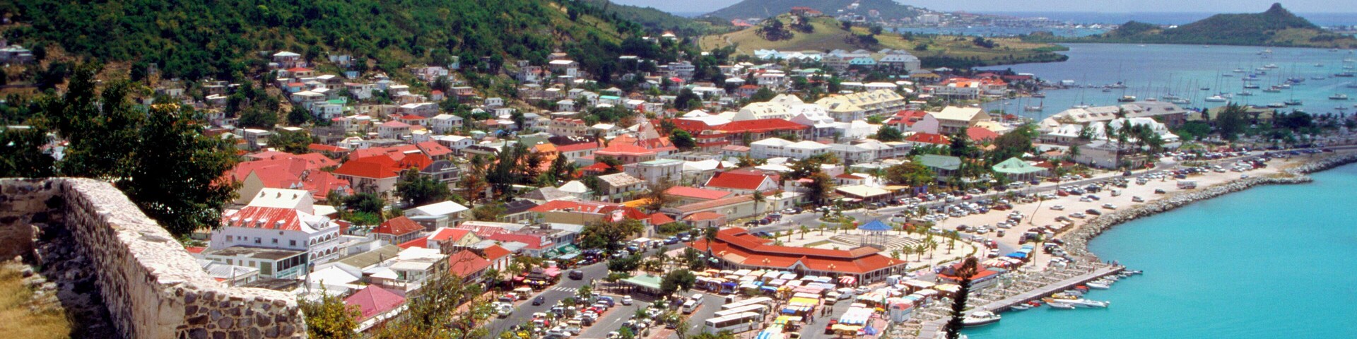 Uma cidade costeira com um forte histórico, edifícios coloridos e um porto de recreio.