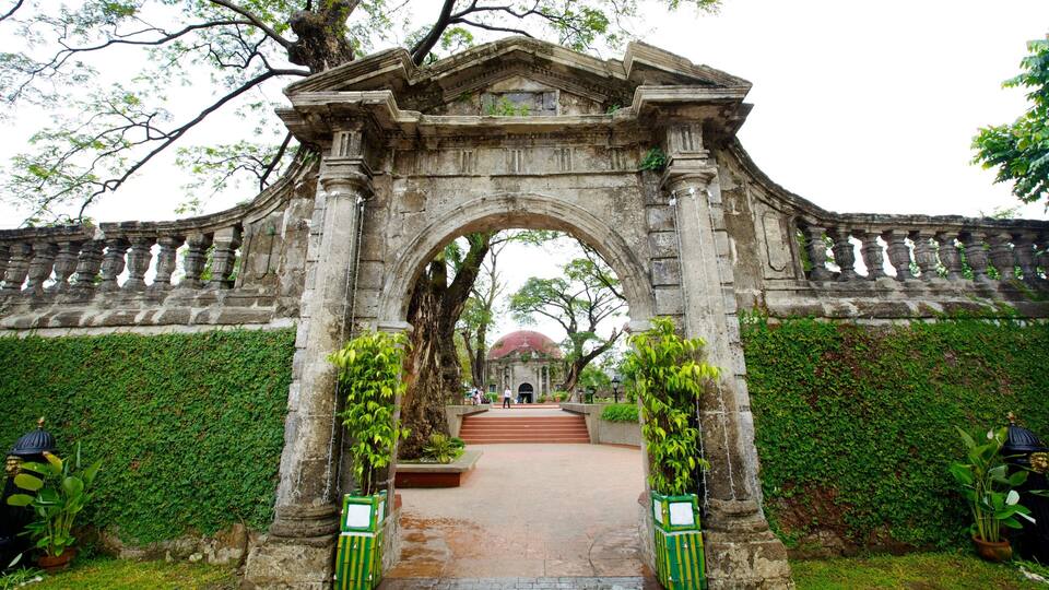 Um antigo arco de pedra com uma cúpula vermelha ao fundo.