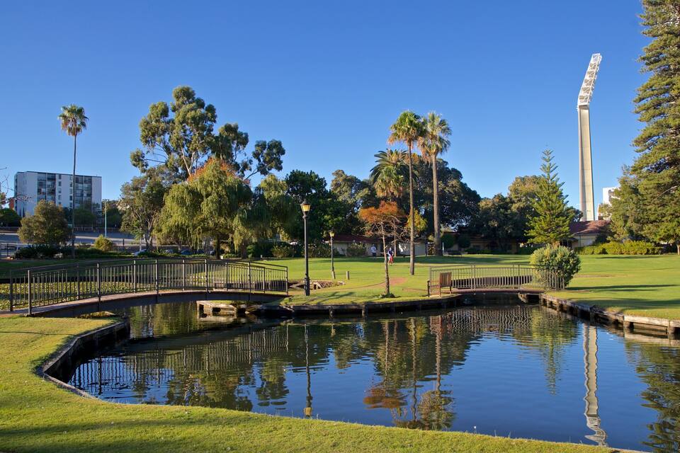 Um parque com lago, ponte e árvores.