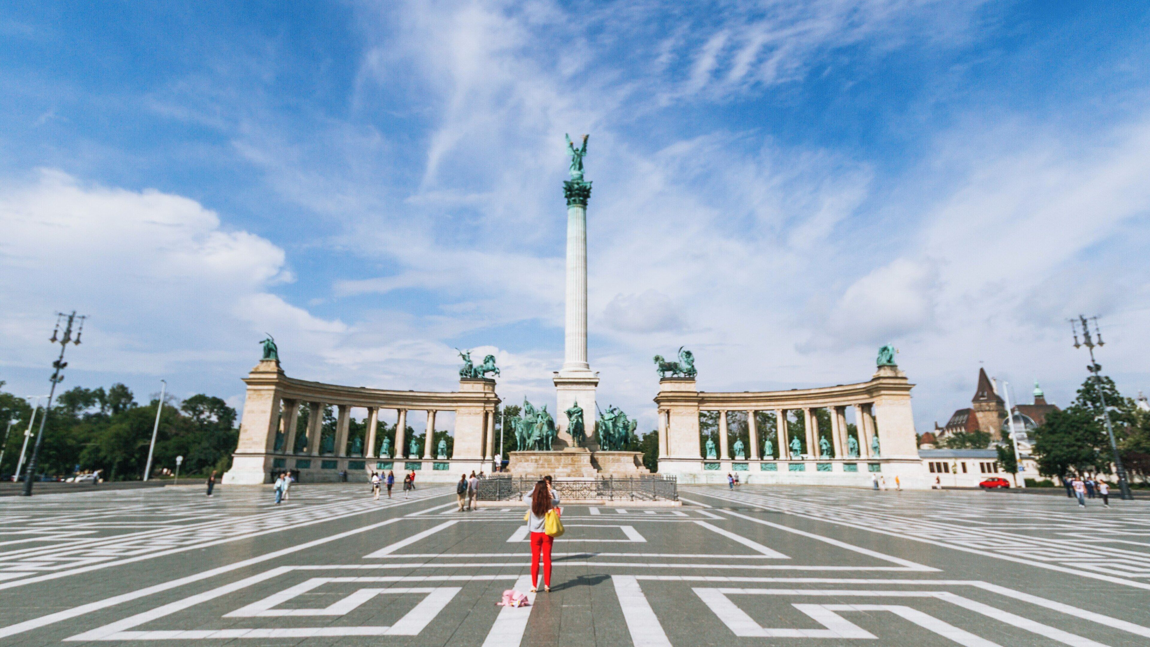 Visit to Heroes' Square in Budapest, Hungary showcases impressive statues and a monumental column under a vibrant blue sky