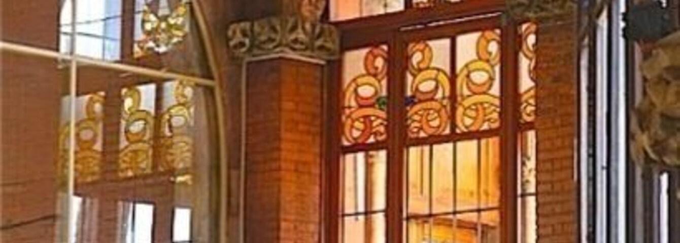 Um edifício com janelas em arco e uma porta decorativa com vitrais.