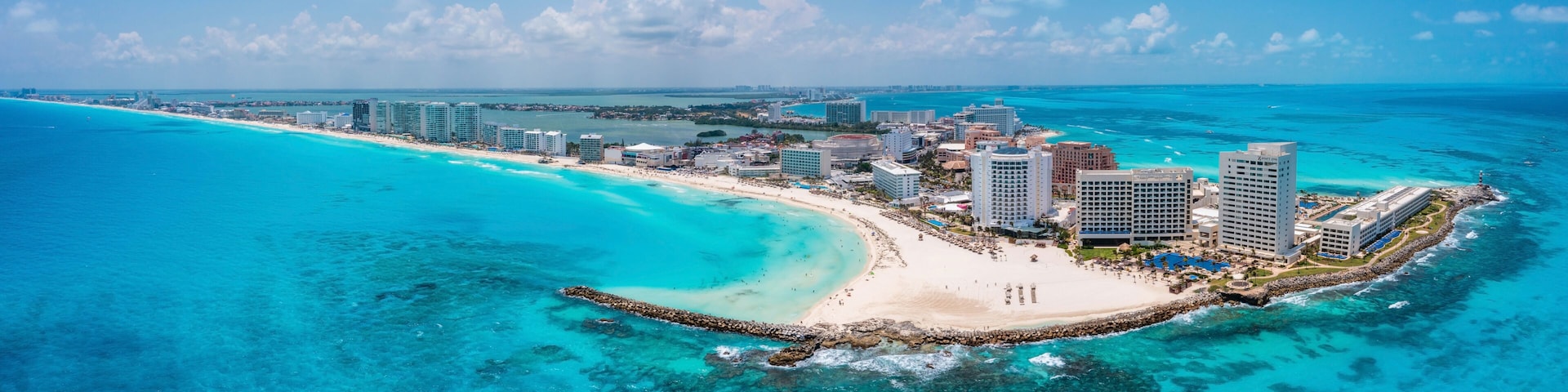 Paisagem costeira com praia, águas turquesas cristalinas e hotéis altos.