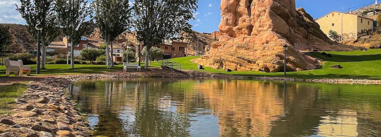 Paisagem rochosa com lago límpido refletindo o céu e as árvores.