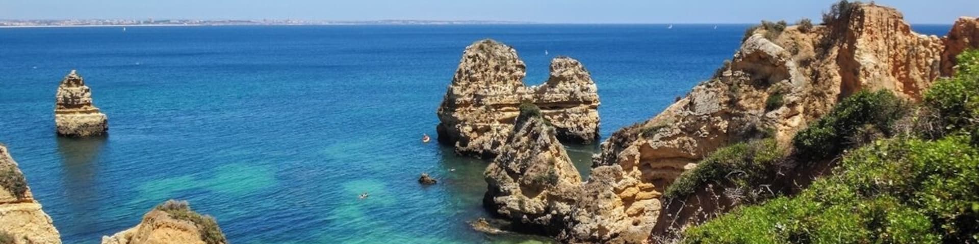 Uma praia costeira com formações rochosas e água azul cristalina.