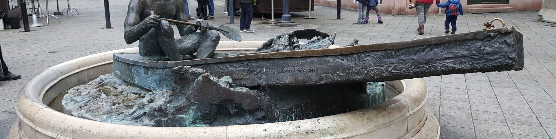 Estátua de bronze de um homem com um barco numa fonte.