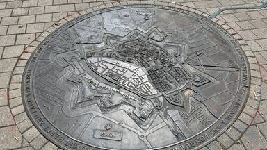 Uma placa de metal detalhada com um mapa e texto, provavelmente uma placa histórica.
