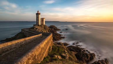 Um farol costeiro, uma escadaria de pedra e um mar calmo com efeito de longa exposição.
