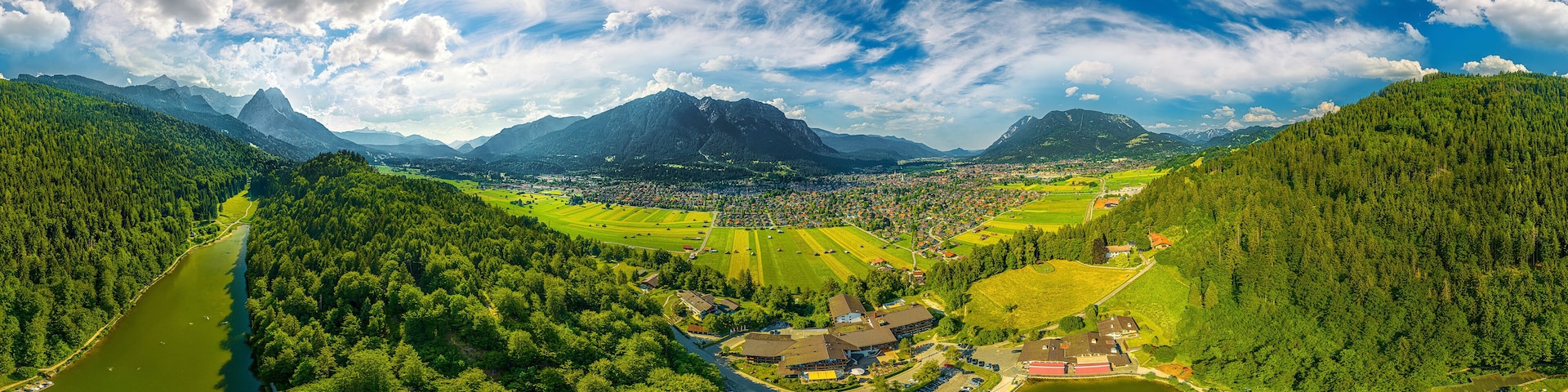 Paisagem montanhosa com um rio, uma cidade e um lago.