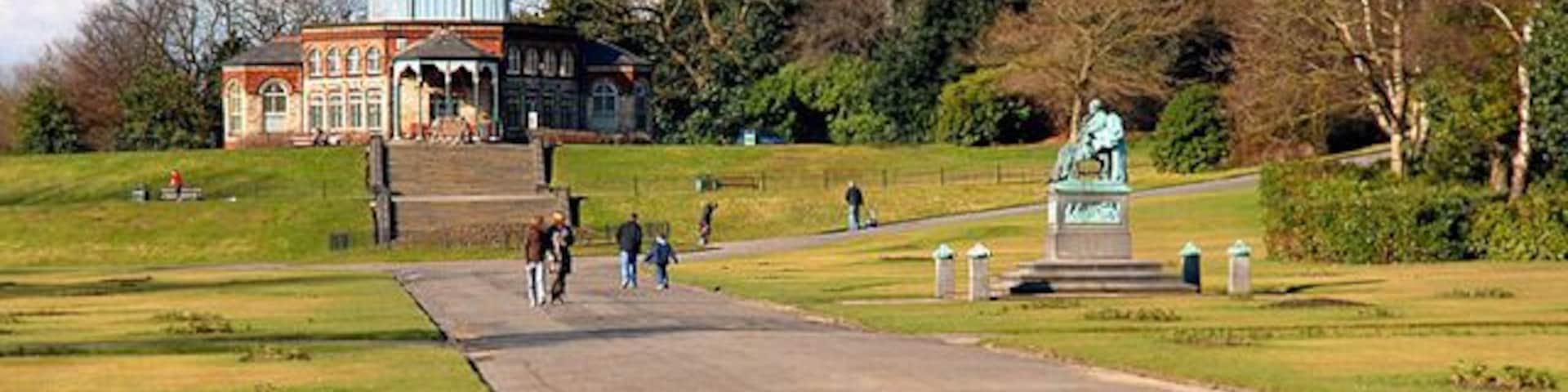 Um parque com um coreto, uma estátua e um caminho.