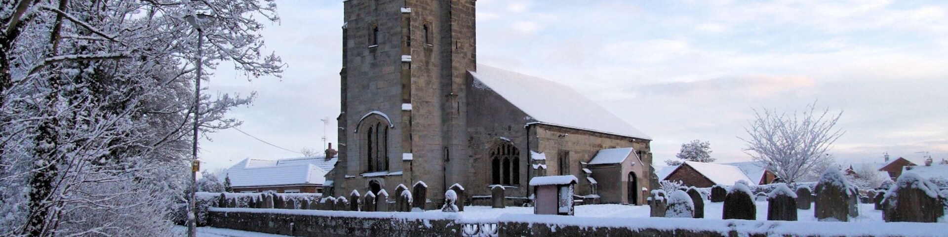 Uma igreja coberta de neve com uma torre alta e janelas em arco.